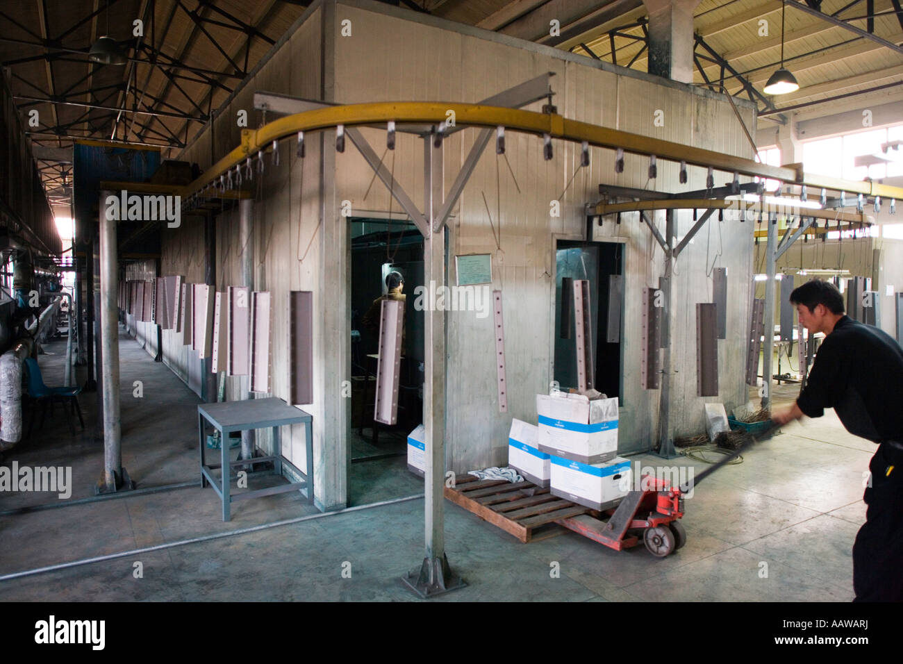 worker in metal fabrication factory loading materials in spray paint ...
