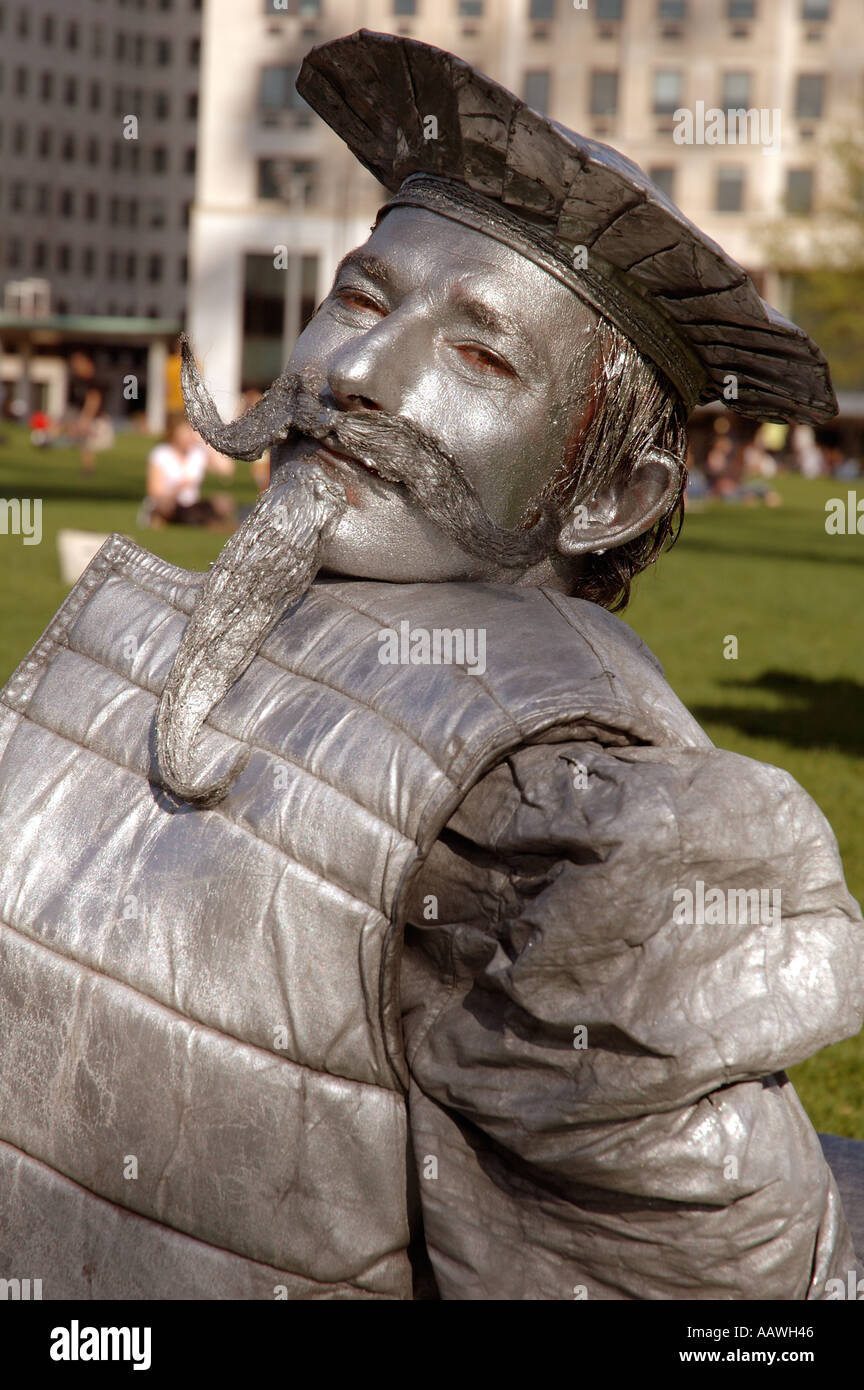 Portrait of a busker street performer painted totally with silver paint ...