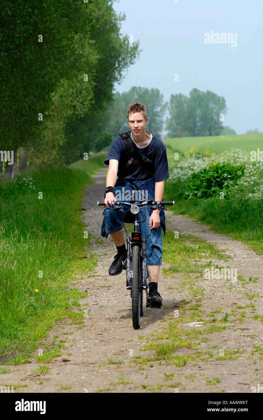 Teenager riding a bike on field path Stock Photo - Alamy