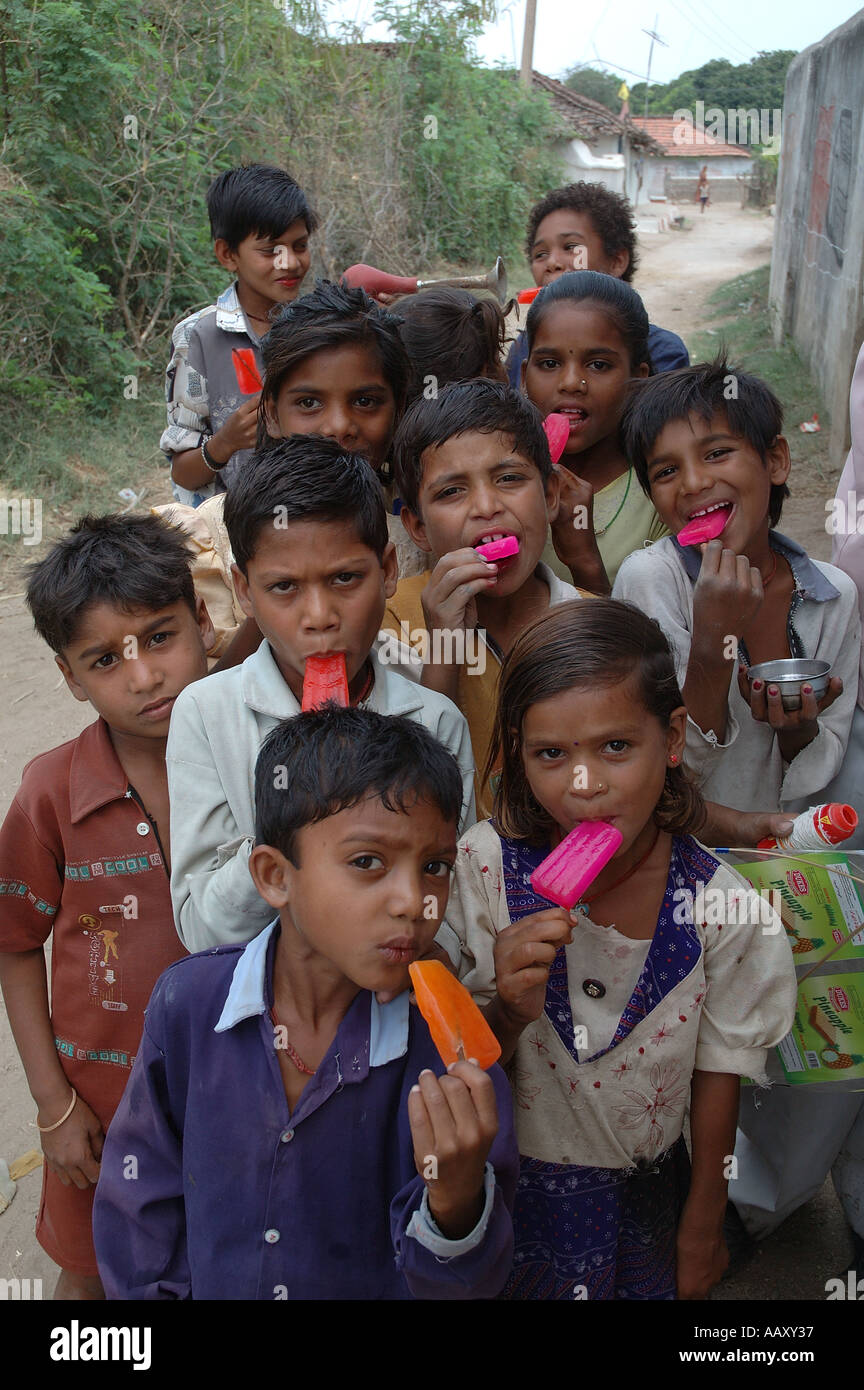 School going children eating red color ice cream in Village Manghawa ...