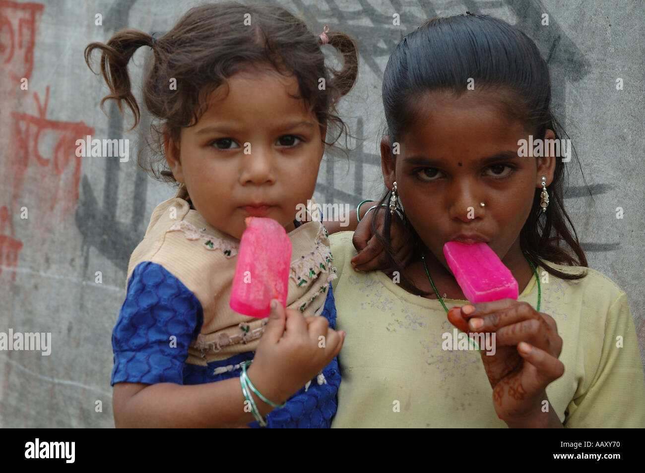 Indian rural children eating red color ice cream in Village Manghawa ...