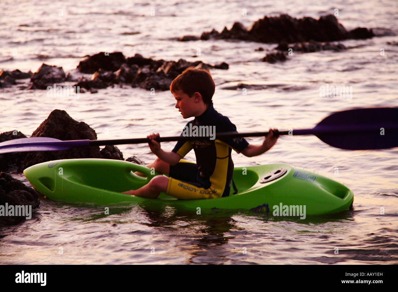 young boy 7 paddling in kayak at sunset Stock Photo - Alamy