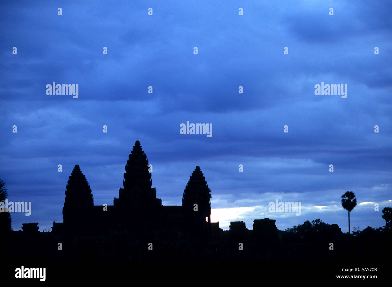 Angkor Wat temple silhouetted against a dark blue cloudy sky at dawn ...