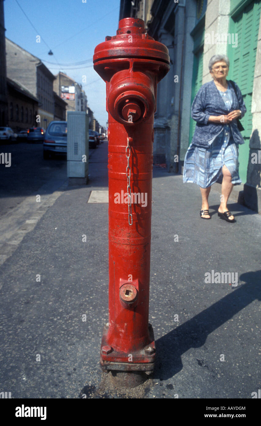 A red fireplug fills the frame top to bottom as an out-of-focus woman ...