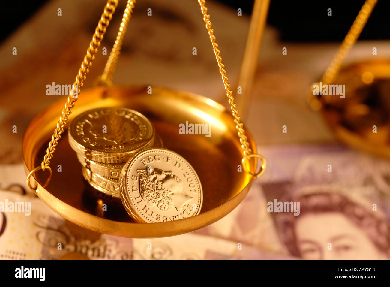 Pound coins in pan of weighing scales over banknotes Stock Photo - Alamy