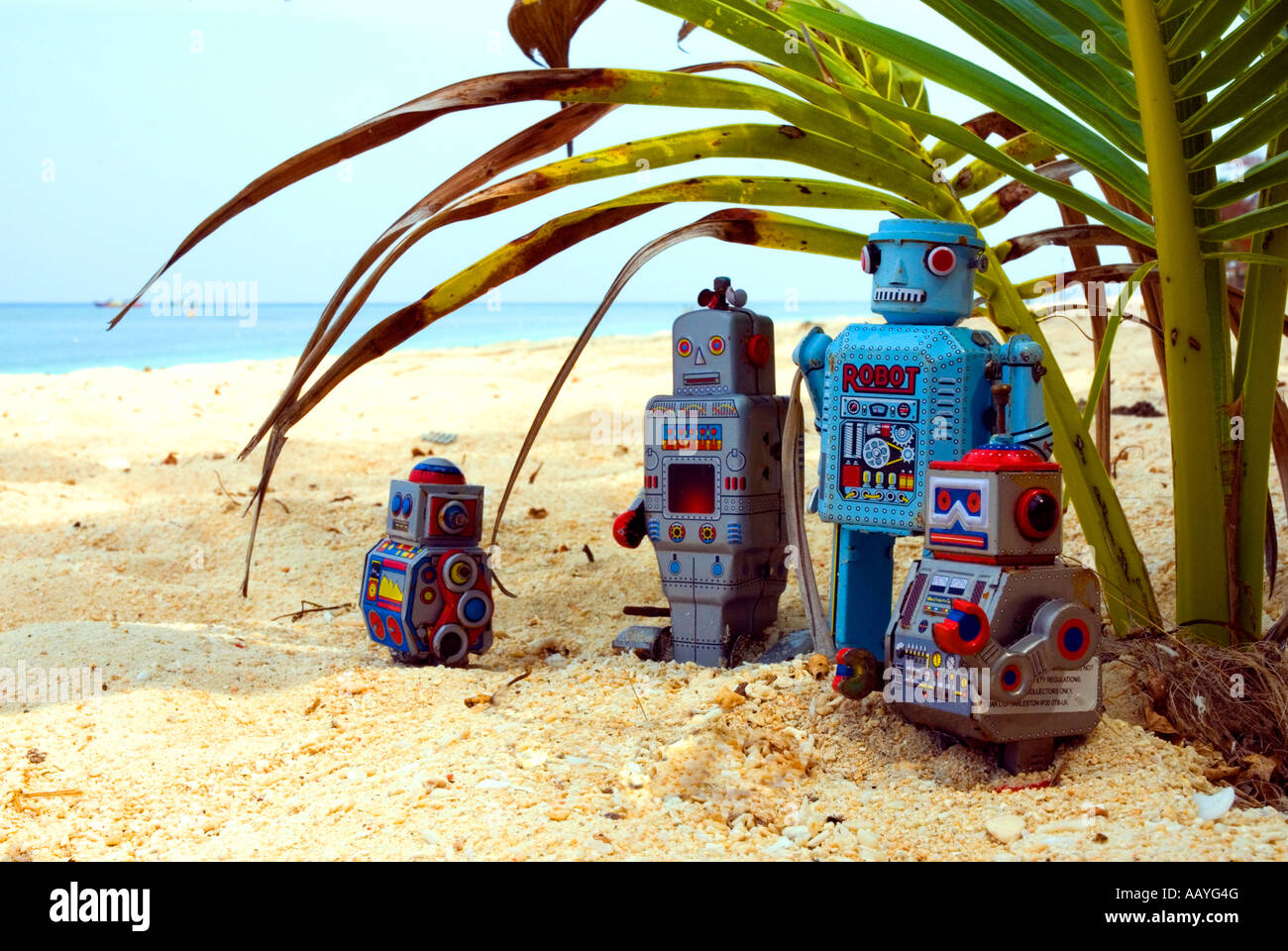 Four toy robots under a palm tree on a tropical beach Stock Photo - Alamy