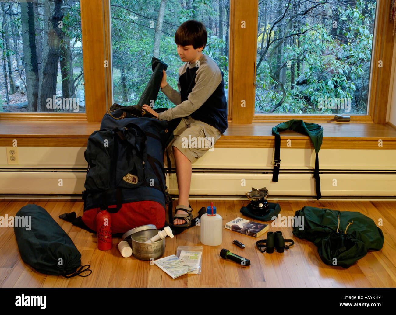 Boy loads tent poles into his backpack as he prepares for a camping ...