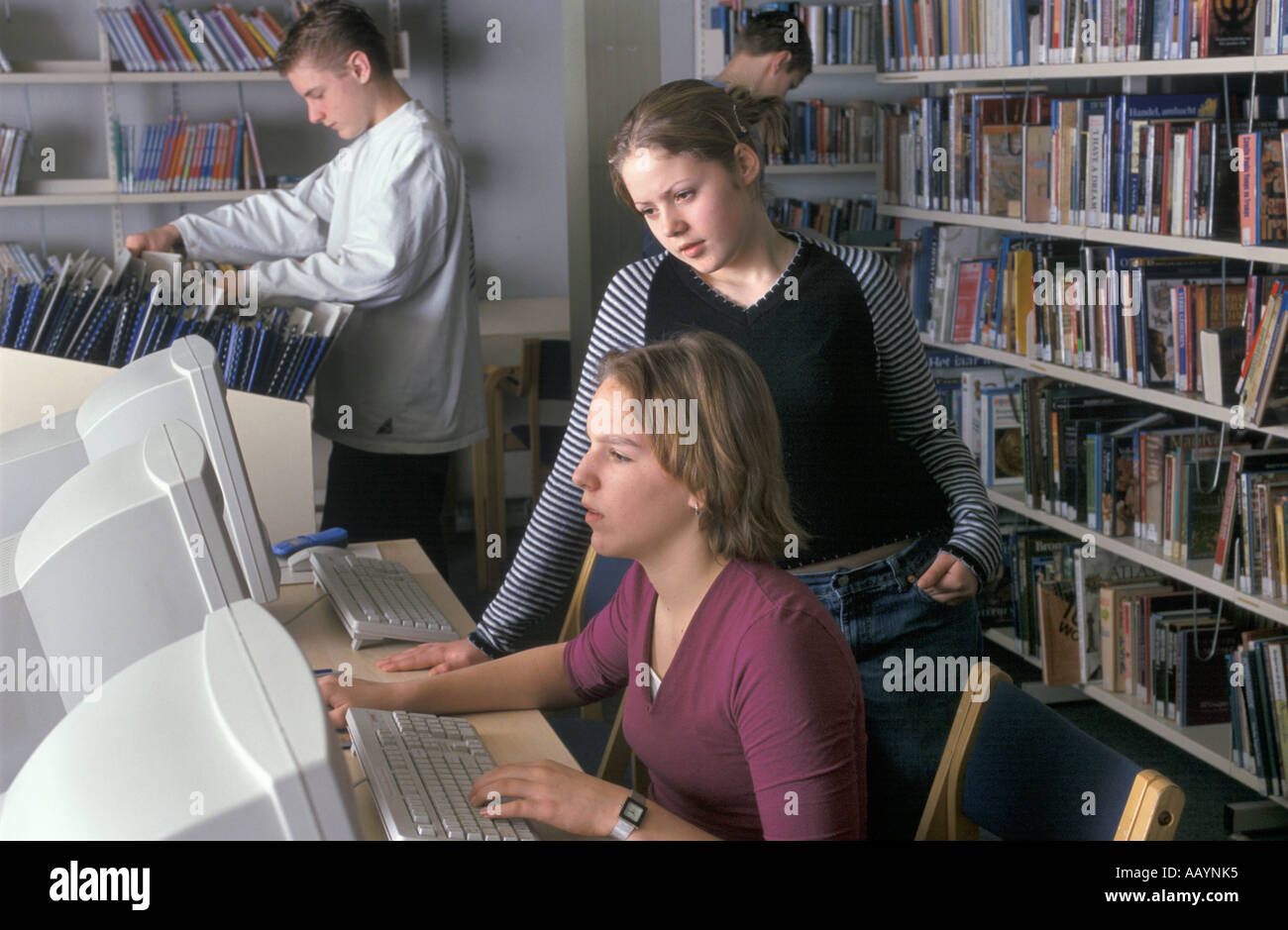 Group of teenage boys and girls behind computer in the library Stock ...