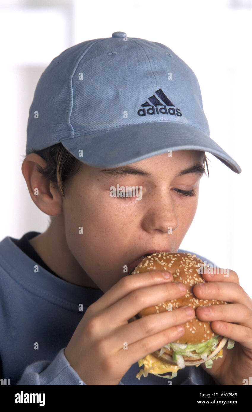 Teenage boy eating hamburger Stock Photo - Alamy