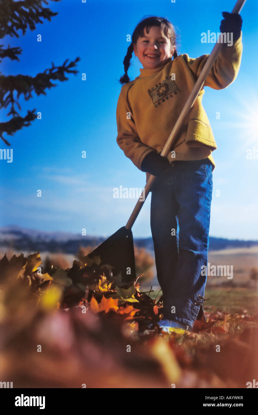 vertical of young girl raking leaves in autumn Stock Photo - Alamy