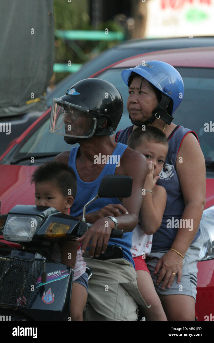 "A family of four travel on a scooter,waiting at traffic lights,one ...