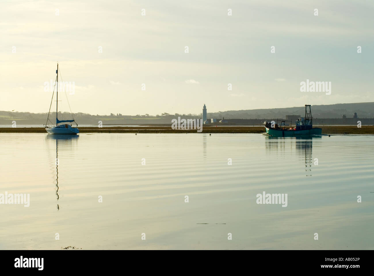 A fishing boat leaves Keyhaven harbour with Hurst Spit lighthouse in ...