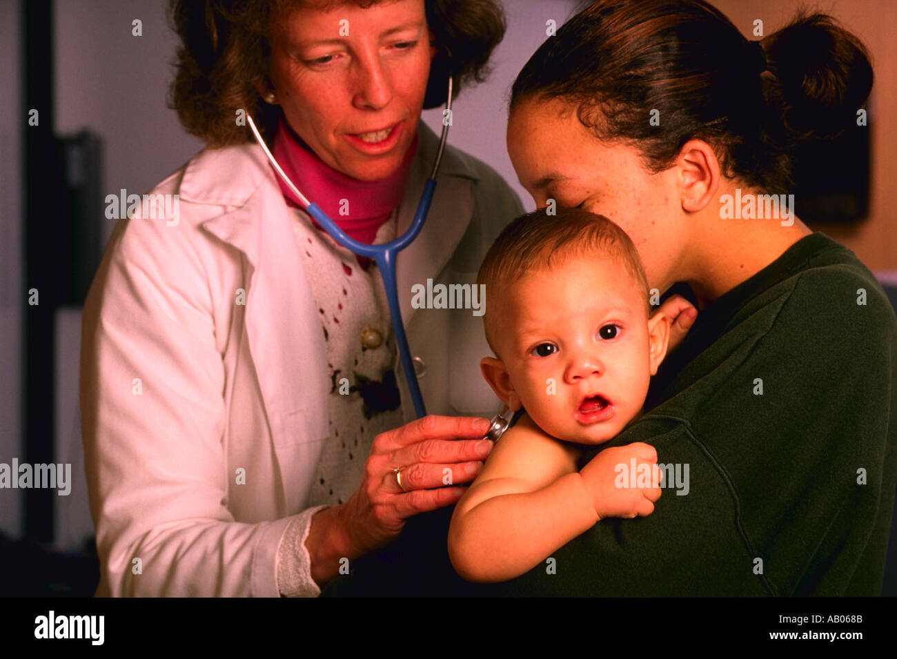 Doctor listening to baby lungs with stethescope with mother holds child ...