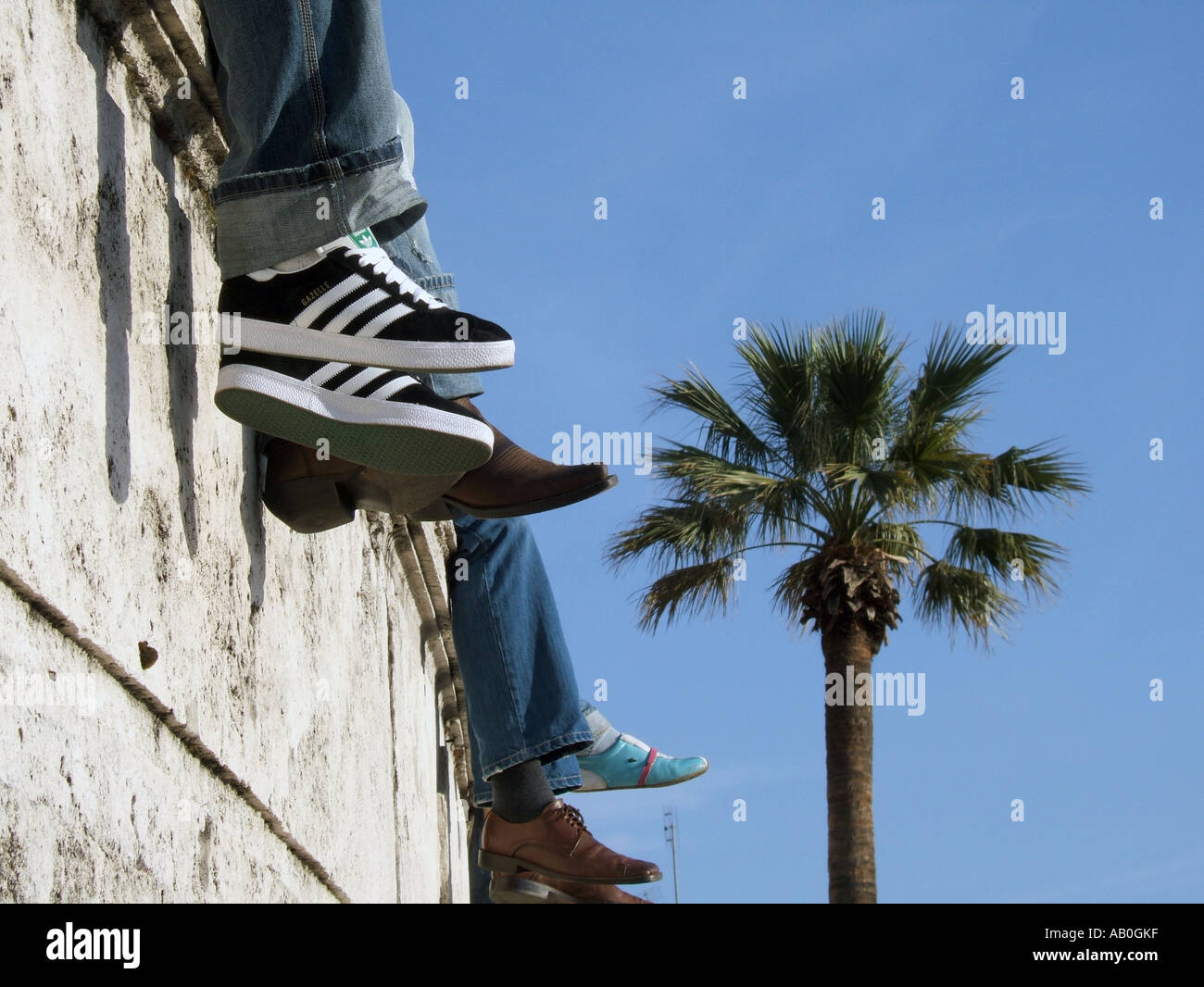 close up of people's feet sitting on wall by spanish steps in rome ...