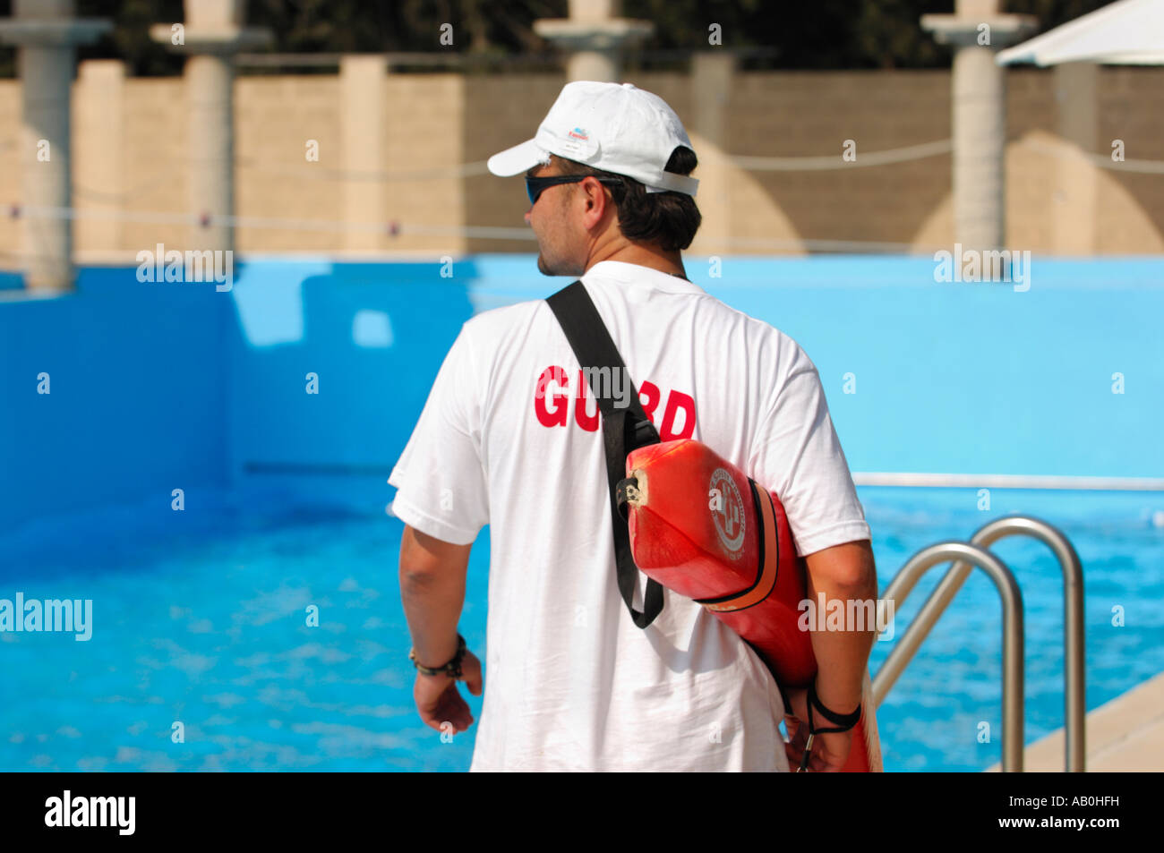Life guard walking along a pool in a water park with a life saving buoy ...