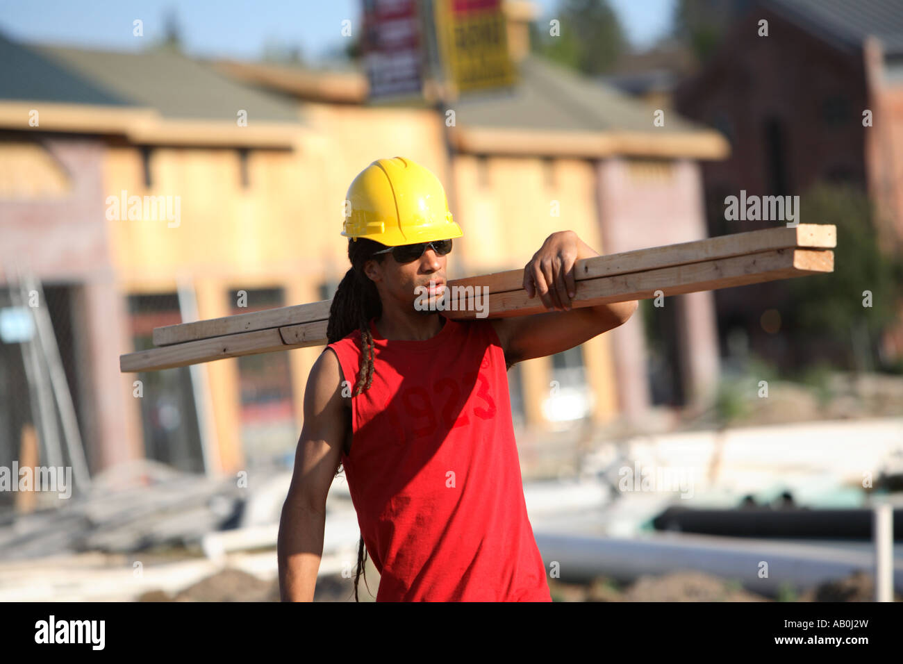 Construction worker carrying two by fours Stock Photo - Alamy