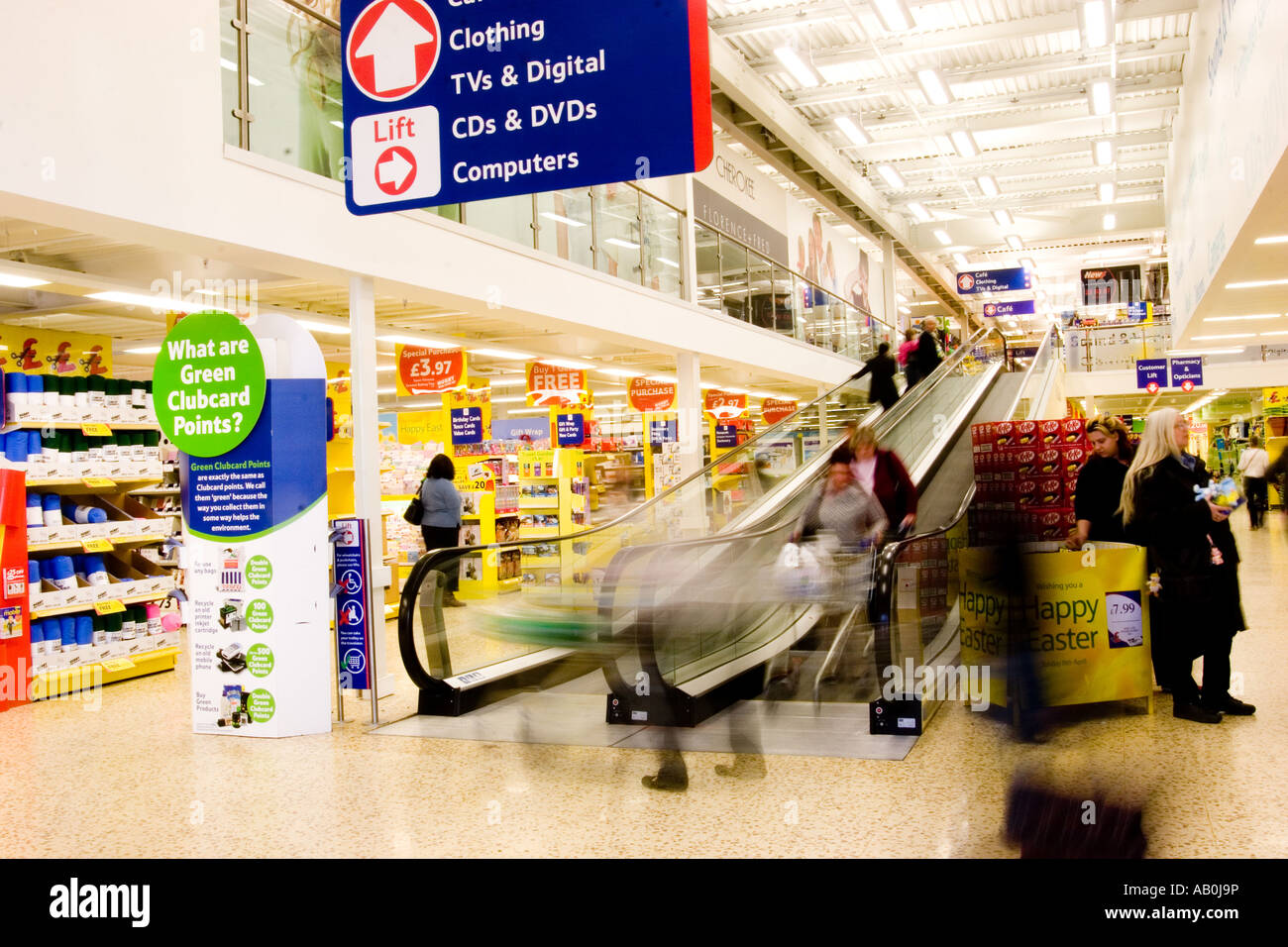 A Busy Supermarket with trolleys and people moving around shopping ...