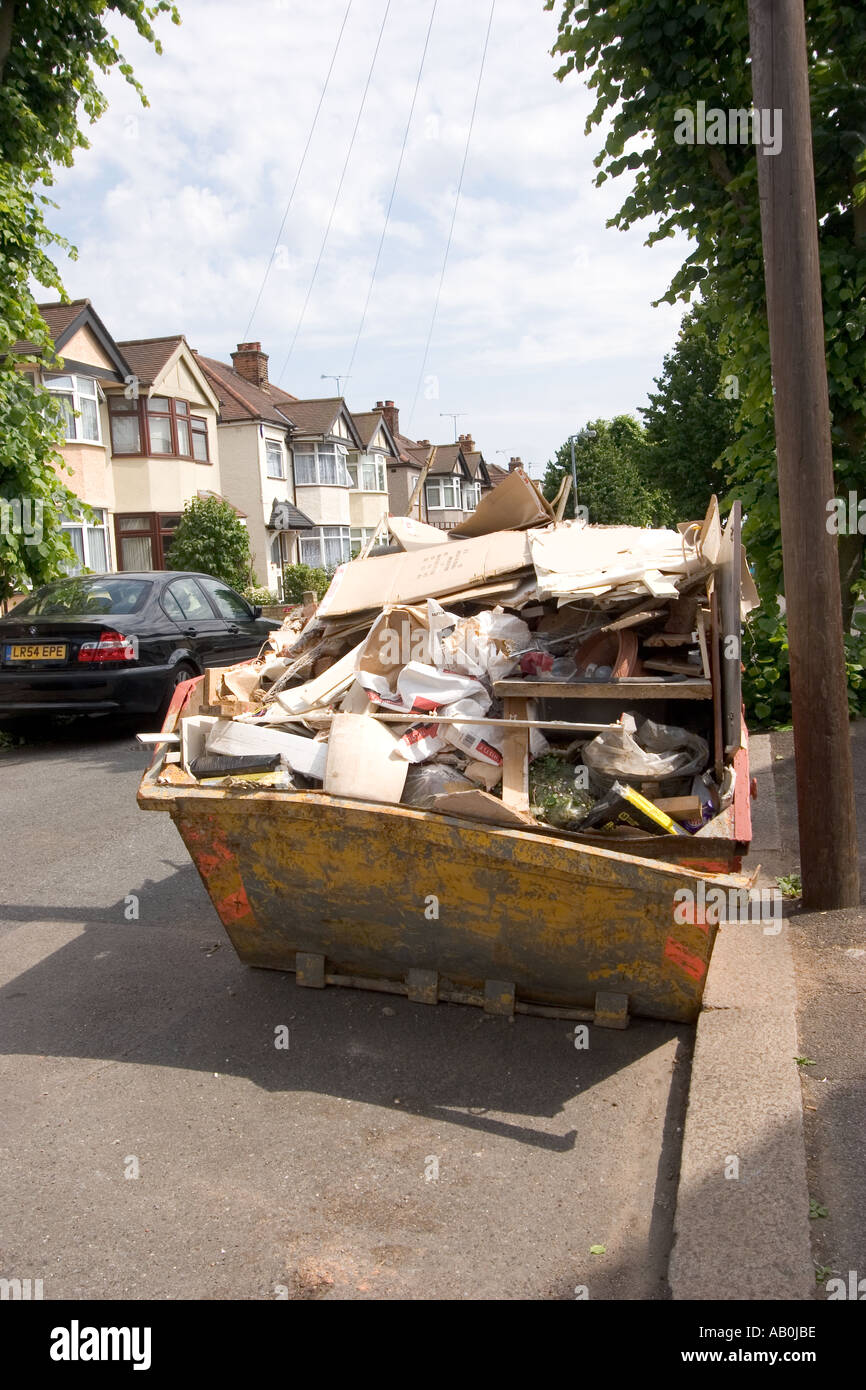Skip in road, full of rubbish outside private residential housing ...