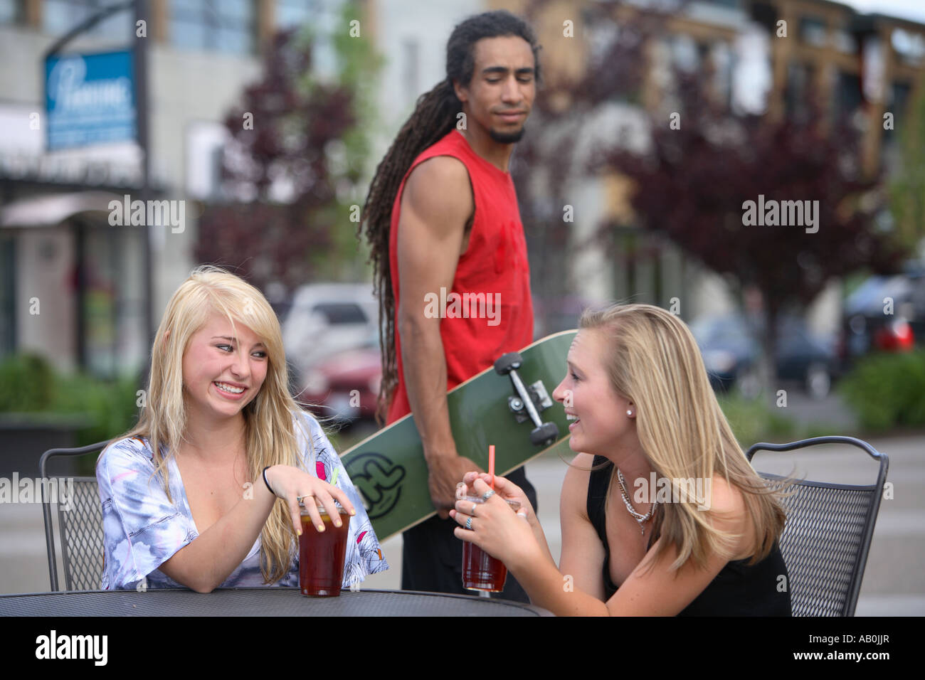 Two girls talking with guy in background checking them out Stock Photo ...