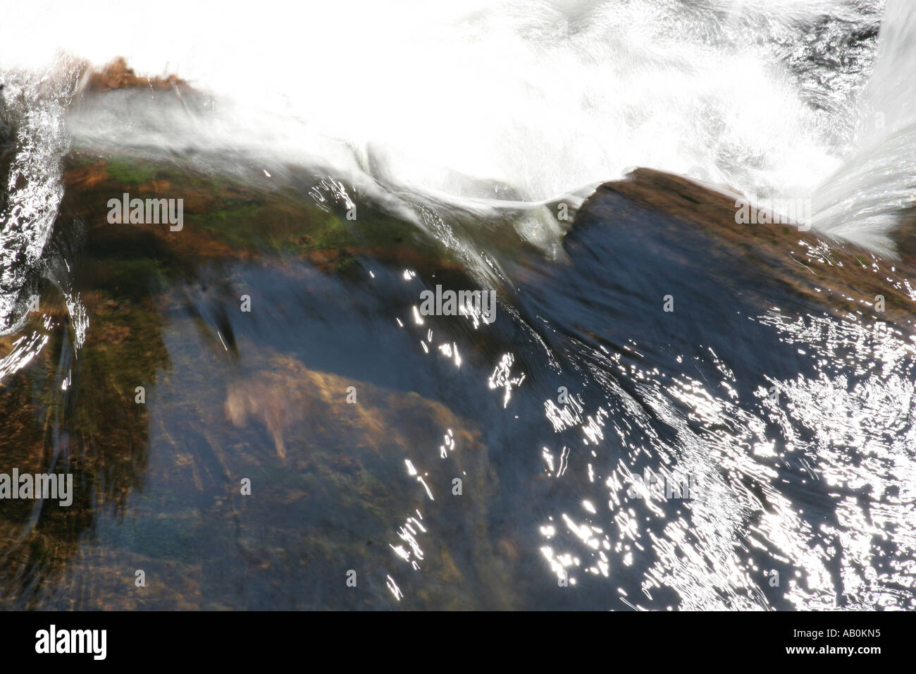 Stream with rocks and flowing water showing reflection of the sunshine ...