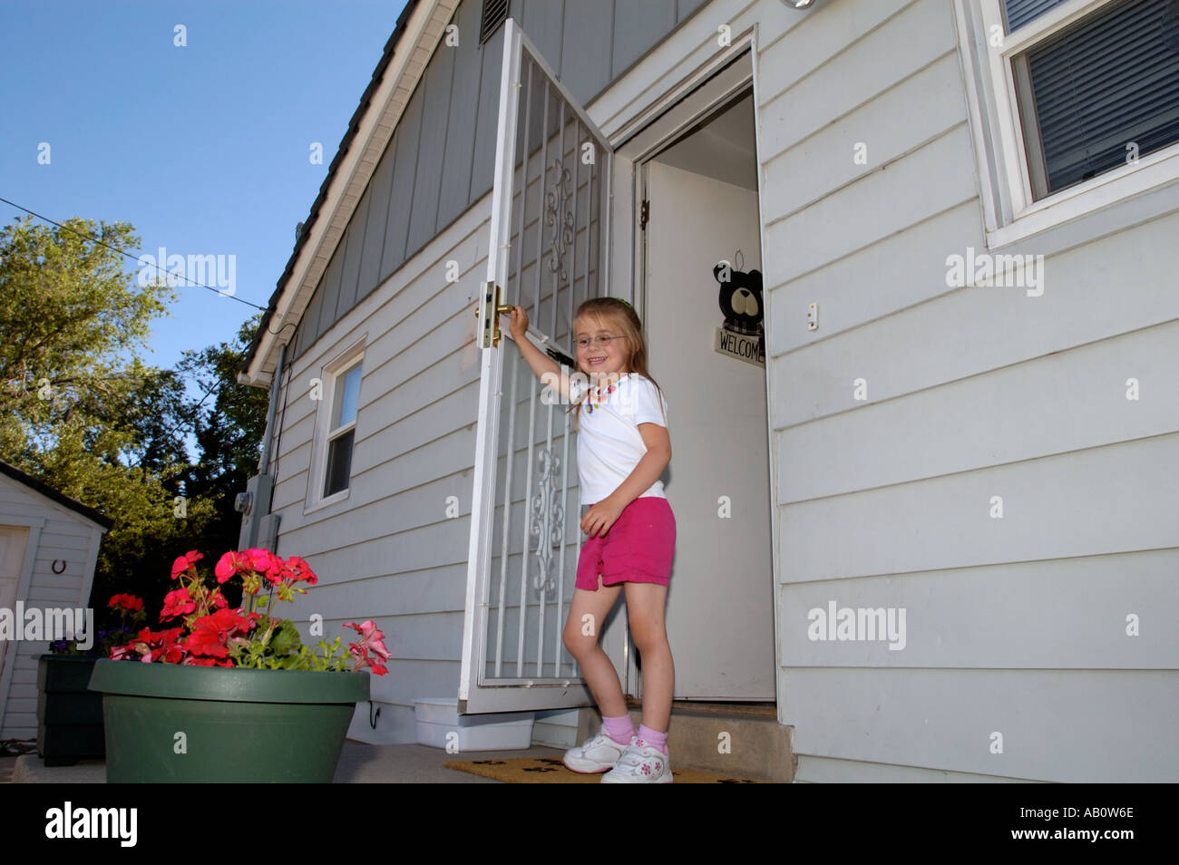 Cute smiling girl walking out of door Stock Photo - Alamy