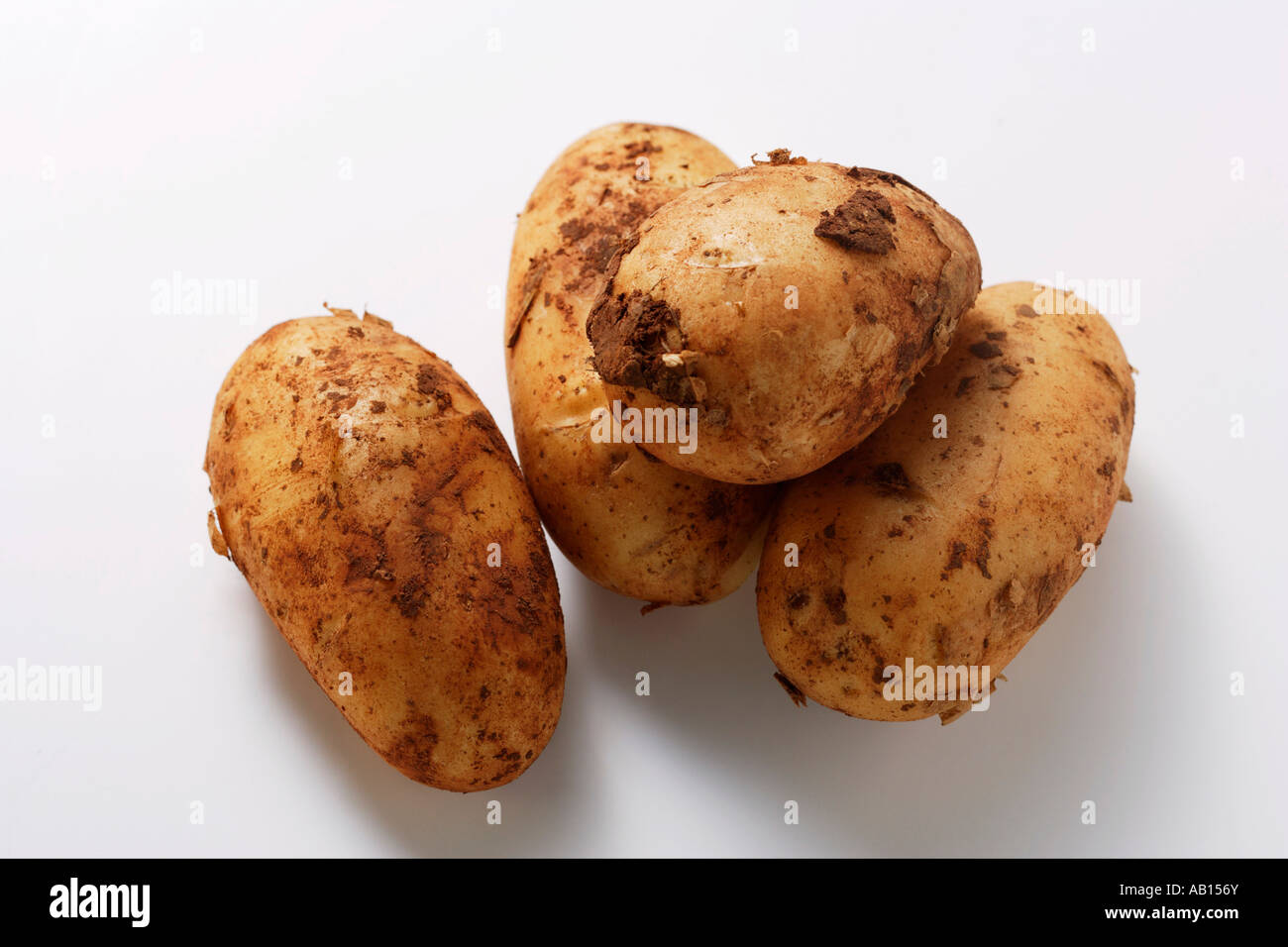 Four potatoes with soil FoodCollection Stock Photo - Alamy