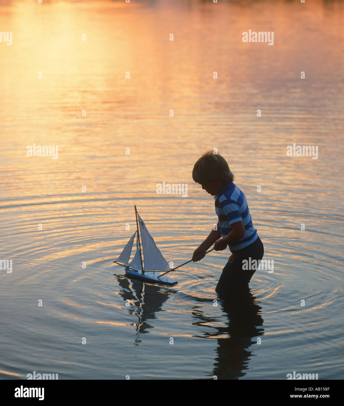 Boy playing with toy sailboat in lake hi-res stock photography and ...