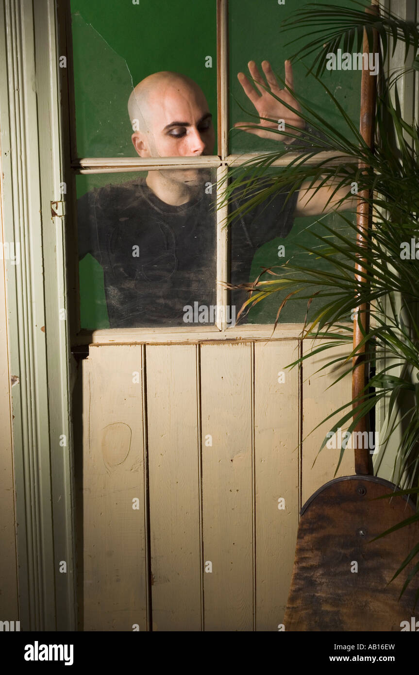 Sinister character peering through a broken window Stock Photo - Alamy