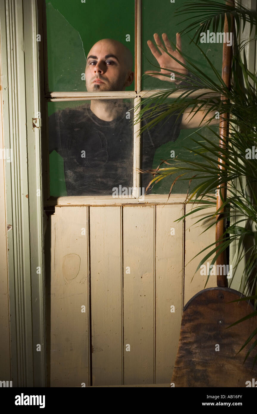 Sinister character peering through a broken window Stock Photo - Alamy