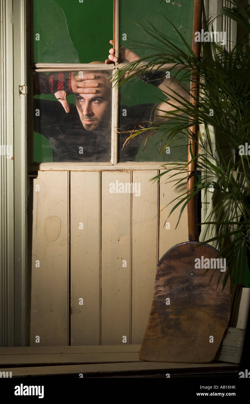 Sinister character peering through a broken window Stock Photo - Alamy