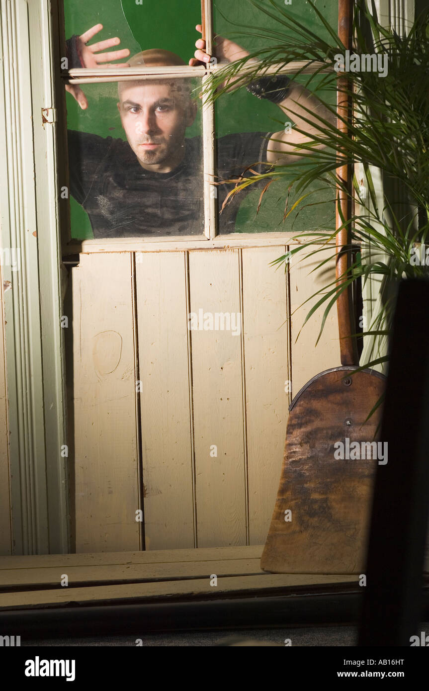 Sinister character peering through a broken window Stock Photo - Alamy