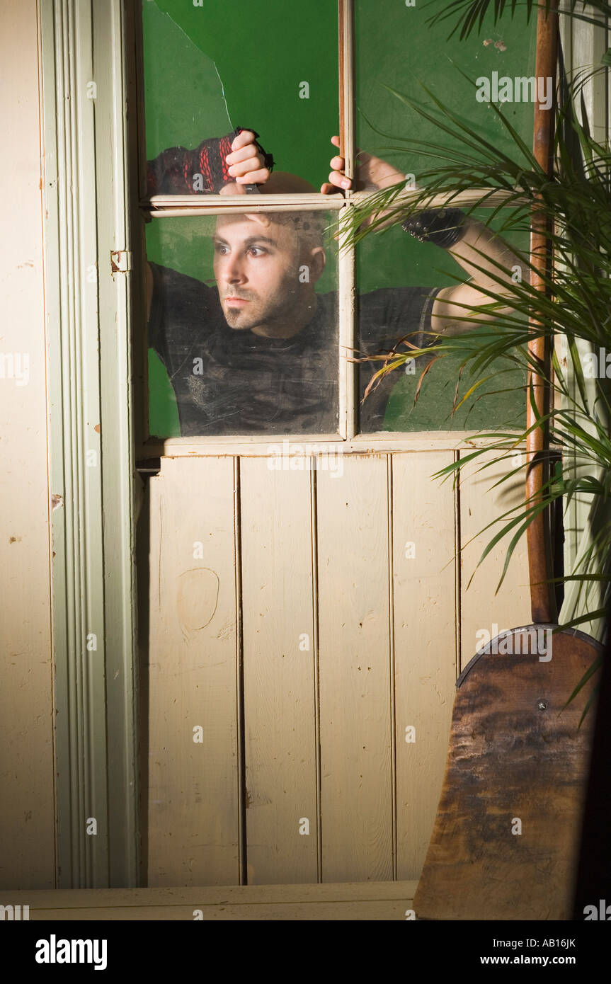Sinister character peering through a broken window Stock Photo - Alamy