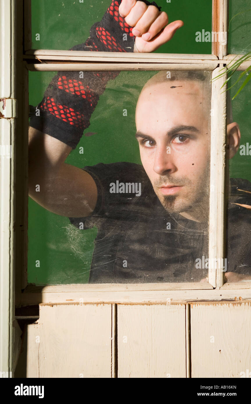 Sinister character peering through a broken window Stock Photo - Alamy