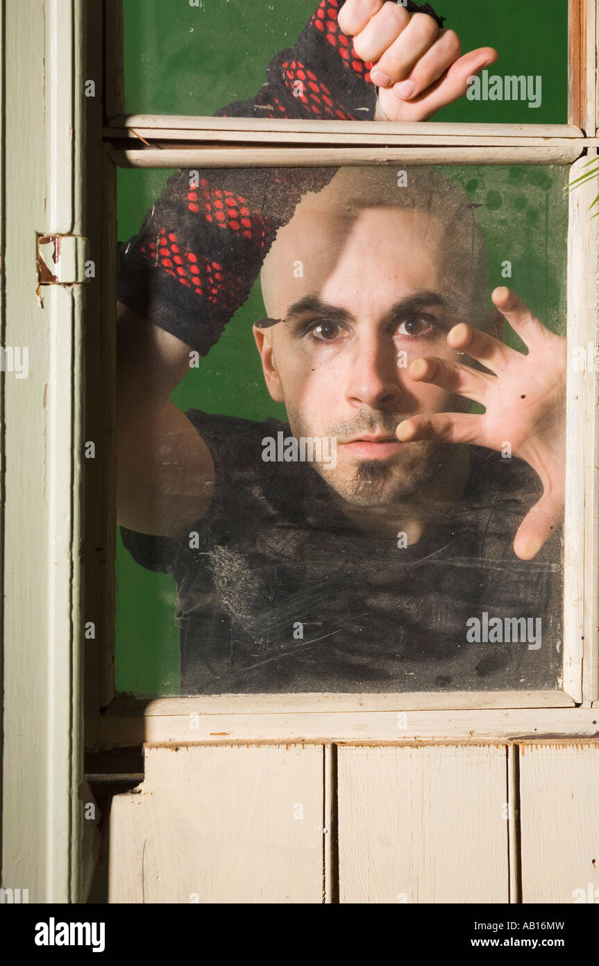 Sinister character peering through a broken window Stock Photo - Alamy