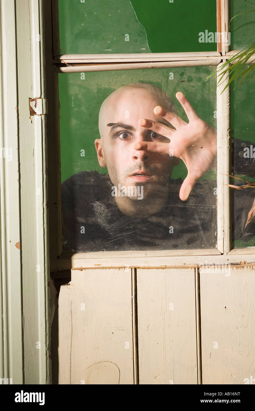 Sinister character peering through a broken window Stock Photo - Alamy