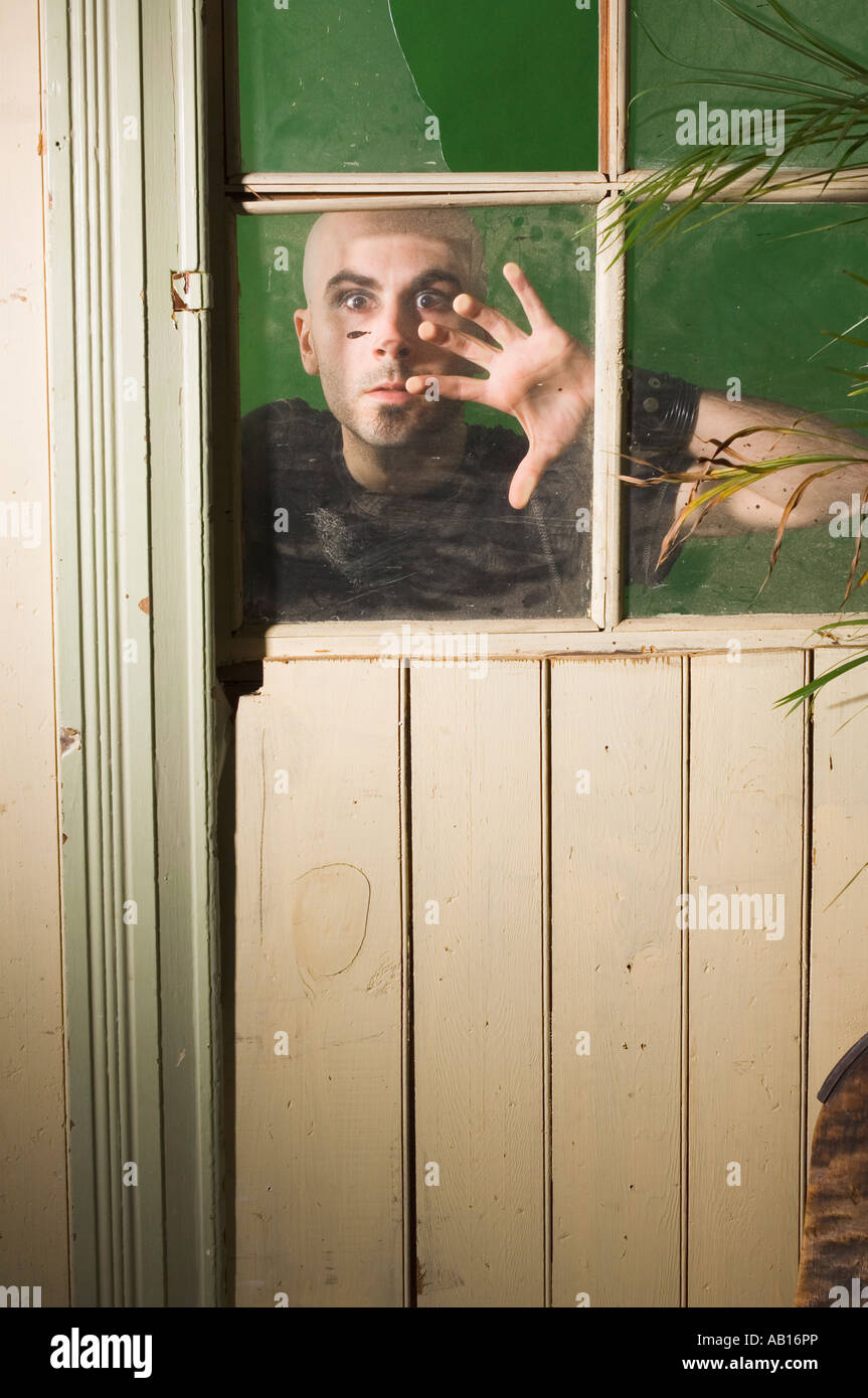 Sinister character peering through a broken window Stock Photo - Alamy