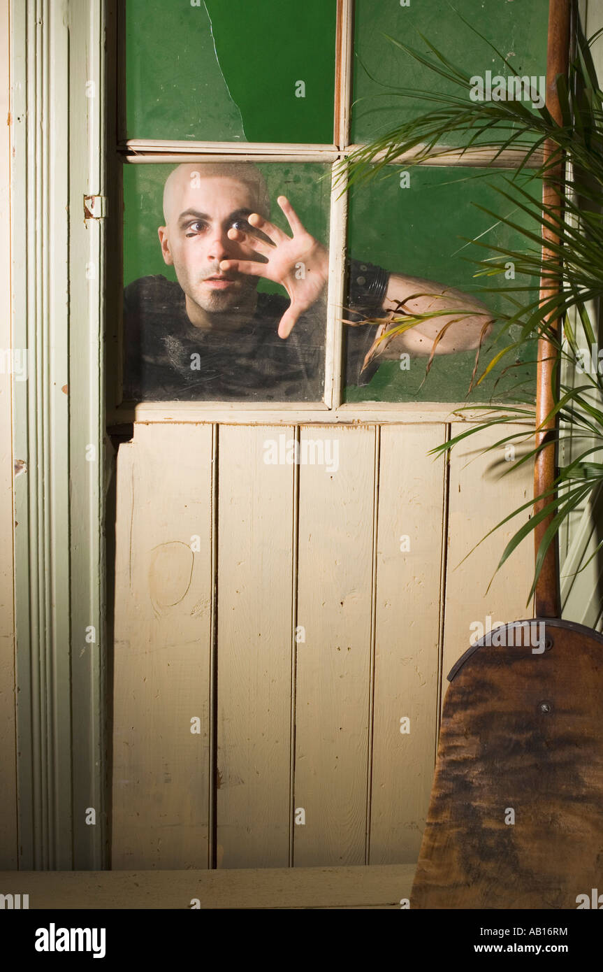 Sinister character peering through a broken window Stock Photo - Alamy