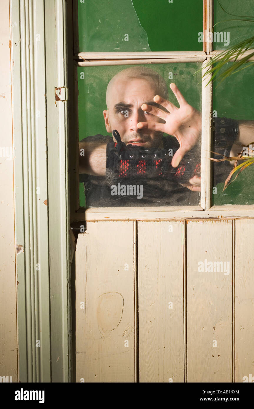 Sinister character peering through a broken window Stock Photo - Alamy