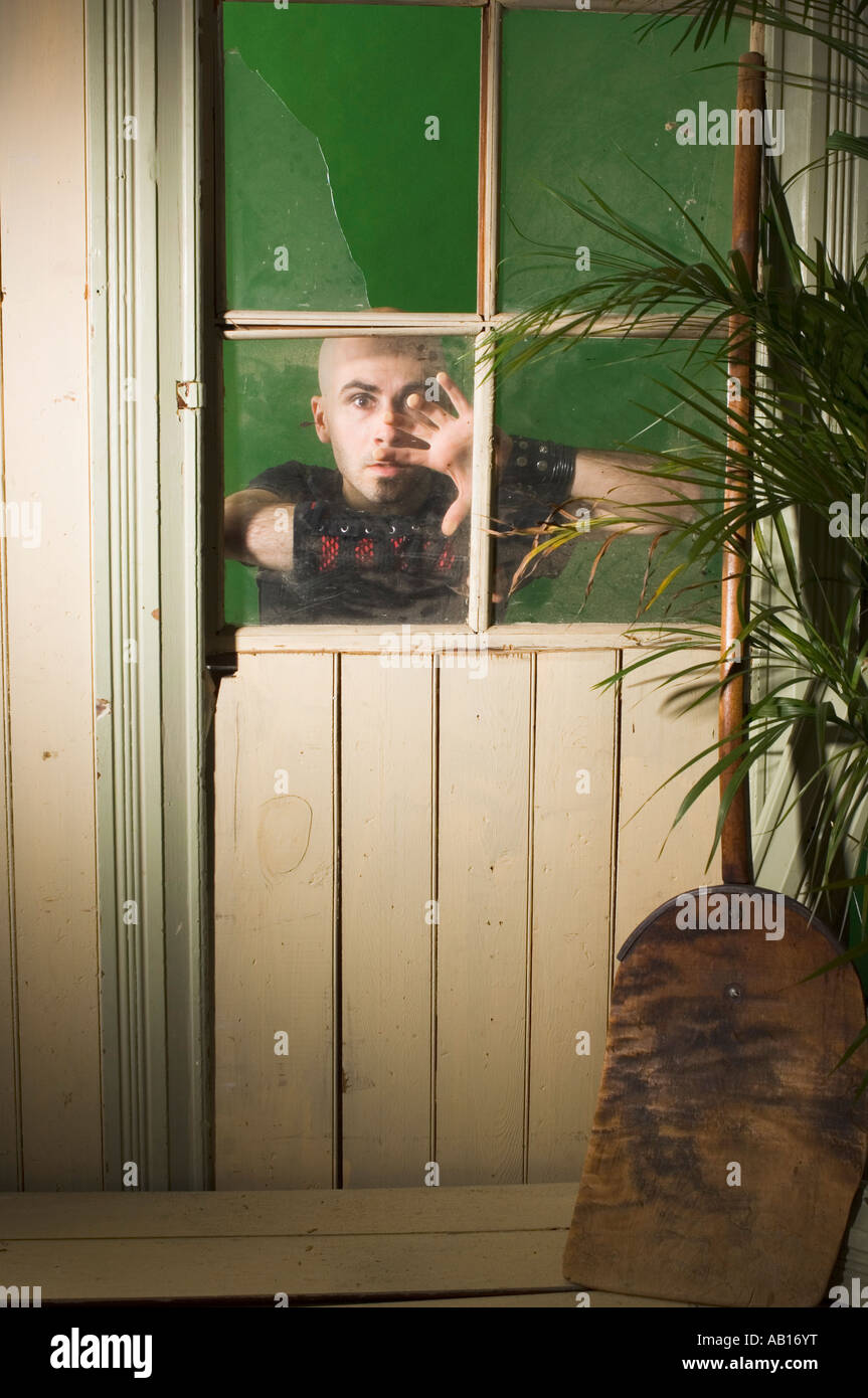 Sinister character peering through a broken window Stock Photo - Alamy