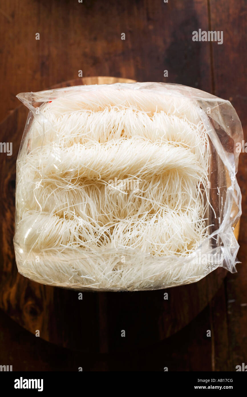 Thin rice noodles in plastic bag on wooden plate FoodCollection Stock ...