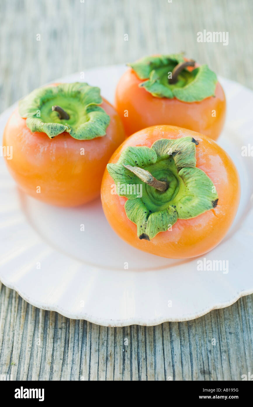 Three Sharon fruits on white plate FoodCollection Stock Photo - Alamy