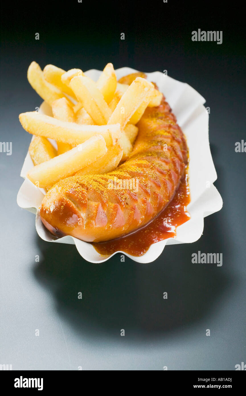 Currywurst sausage with ketchup curry powder chips on paper dish ...