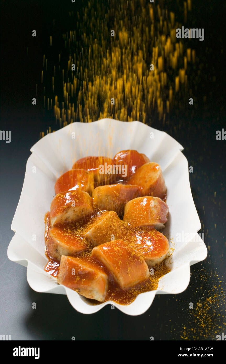 Sprinkling curry powder over sausage in paper dish FoodCollection Stock ...