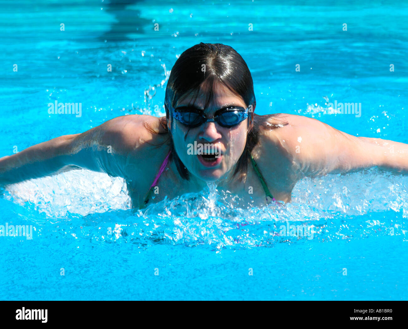 Young woman swimming dolphin butterfly stroke in outdoor pool Stock ...