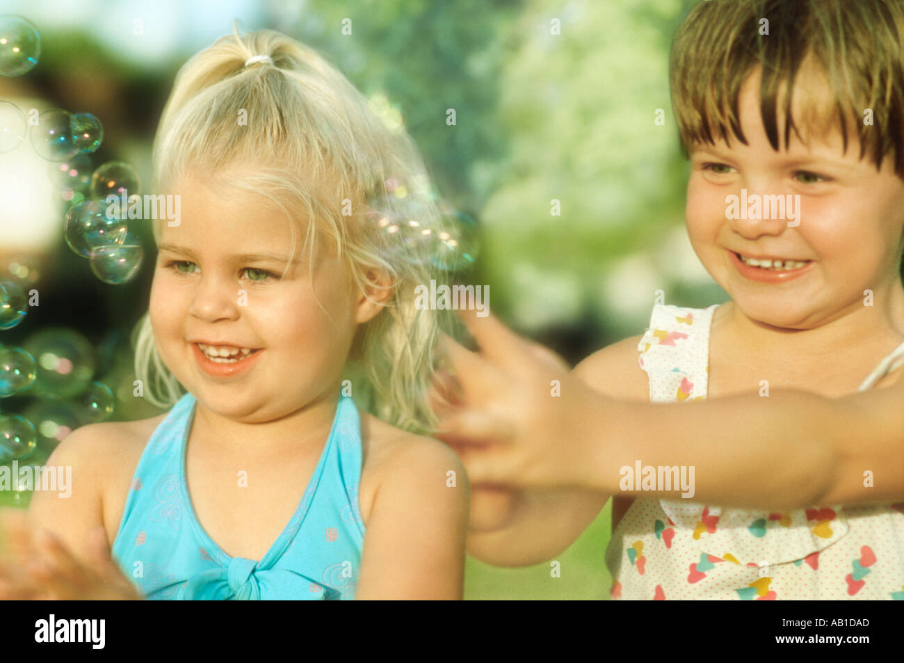 Two young girls catching bubbles outdoors Stock Photo - Alamy