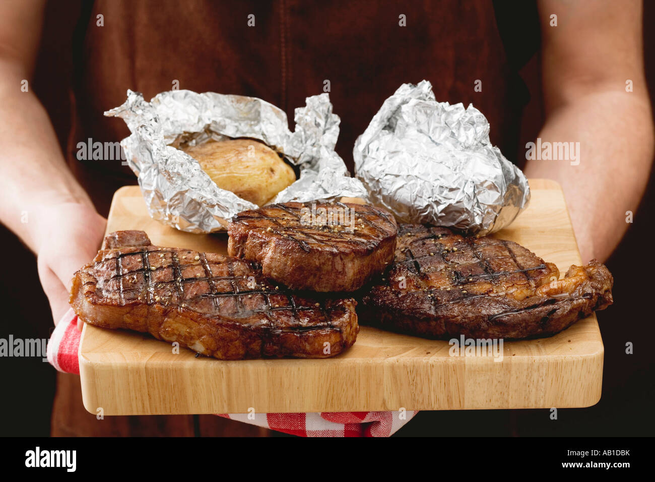Man holding grilled beef steaks on chopping board FoodCollection Stock ...