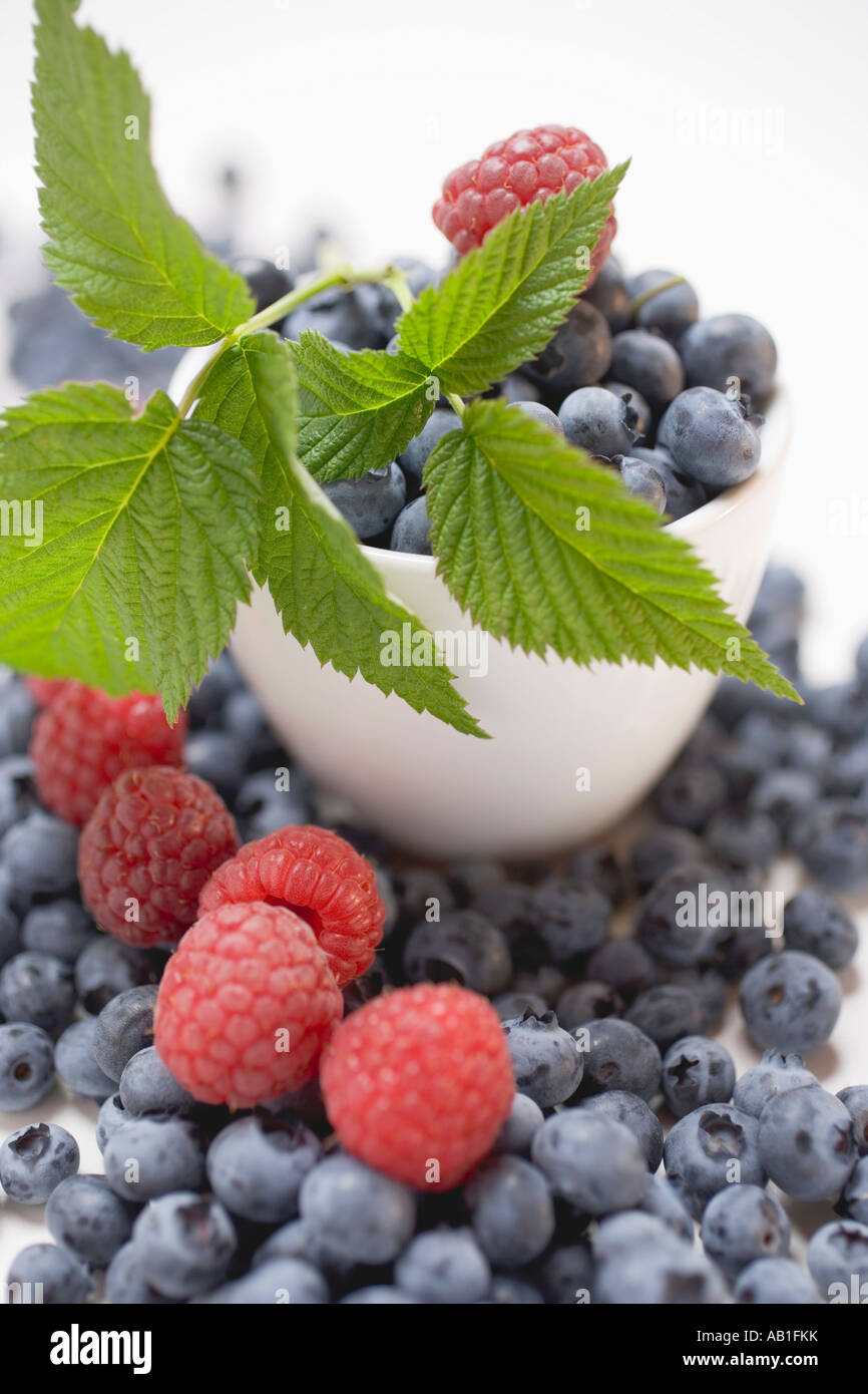Blueberries and raspberries with leaves some in bowl FoodCollection ...