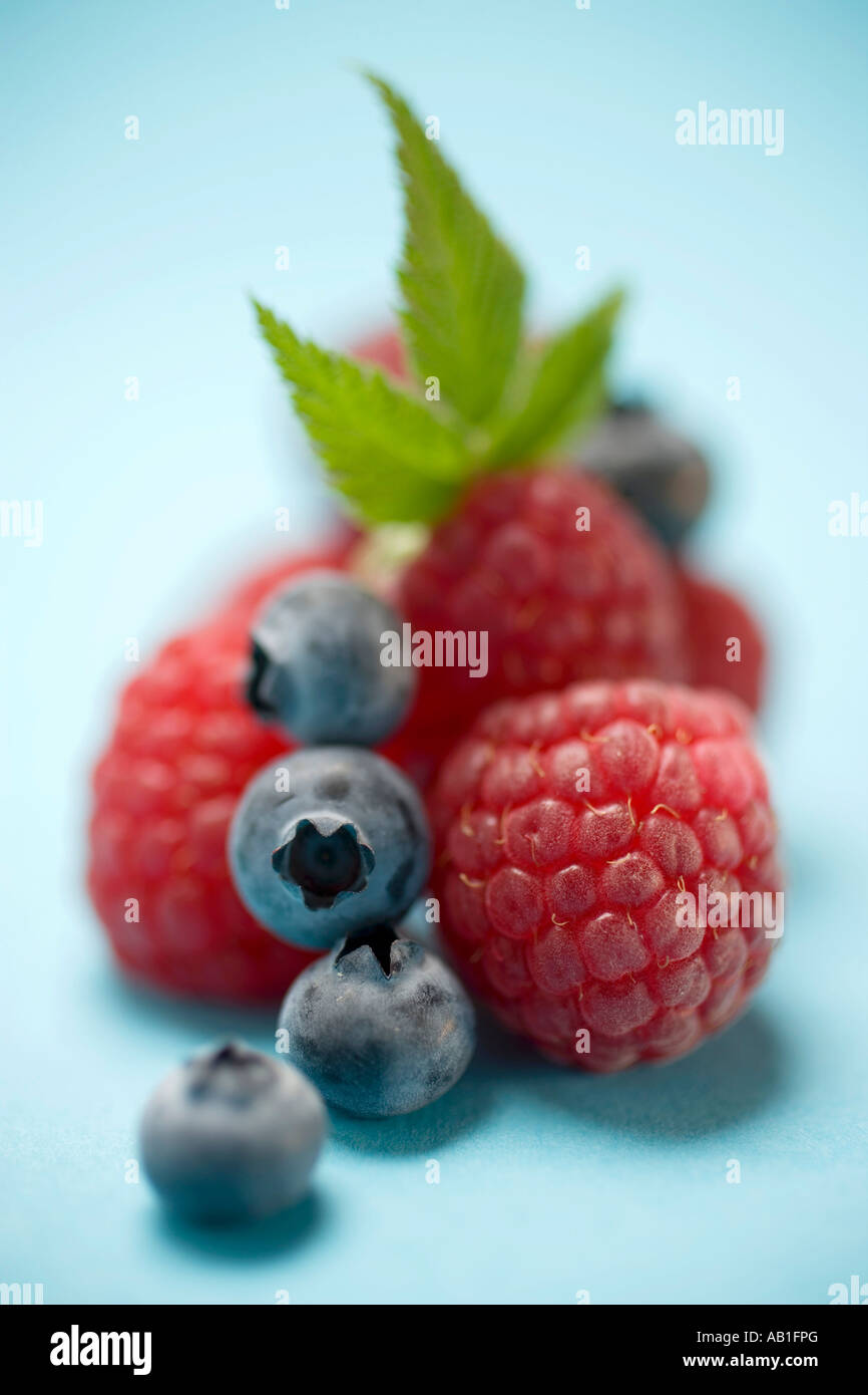 Blueberries and raspberries with leaves on blue background ...