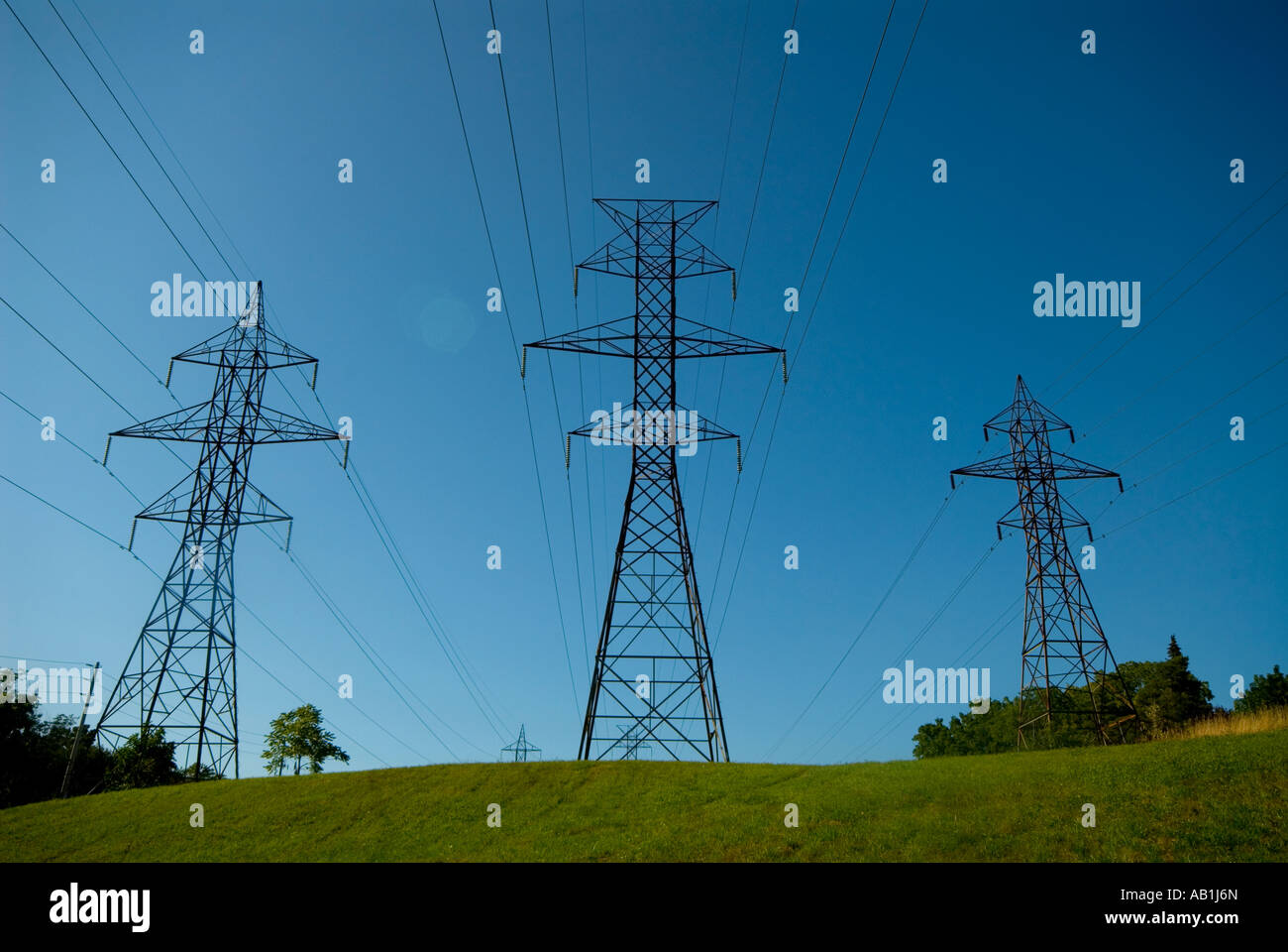 three electric pylons on hilltop flanked by forests Stock Photo - Alamy