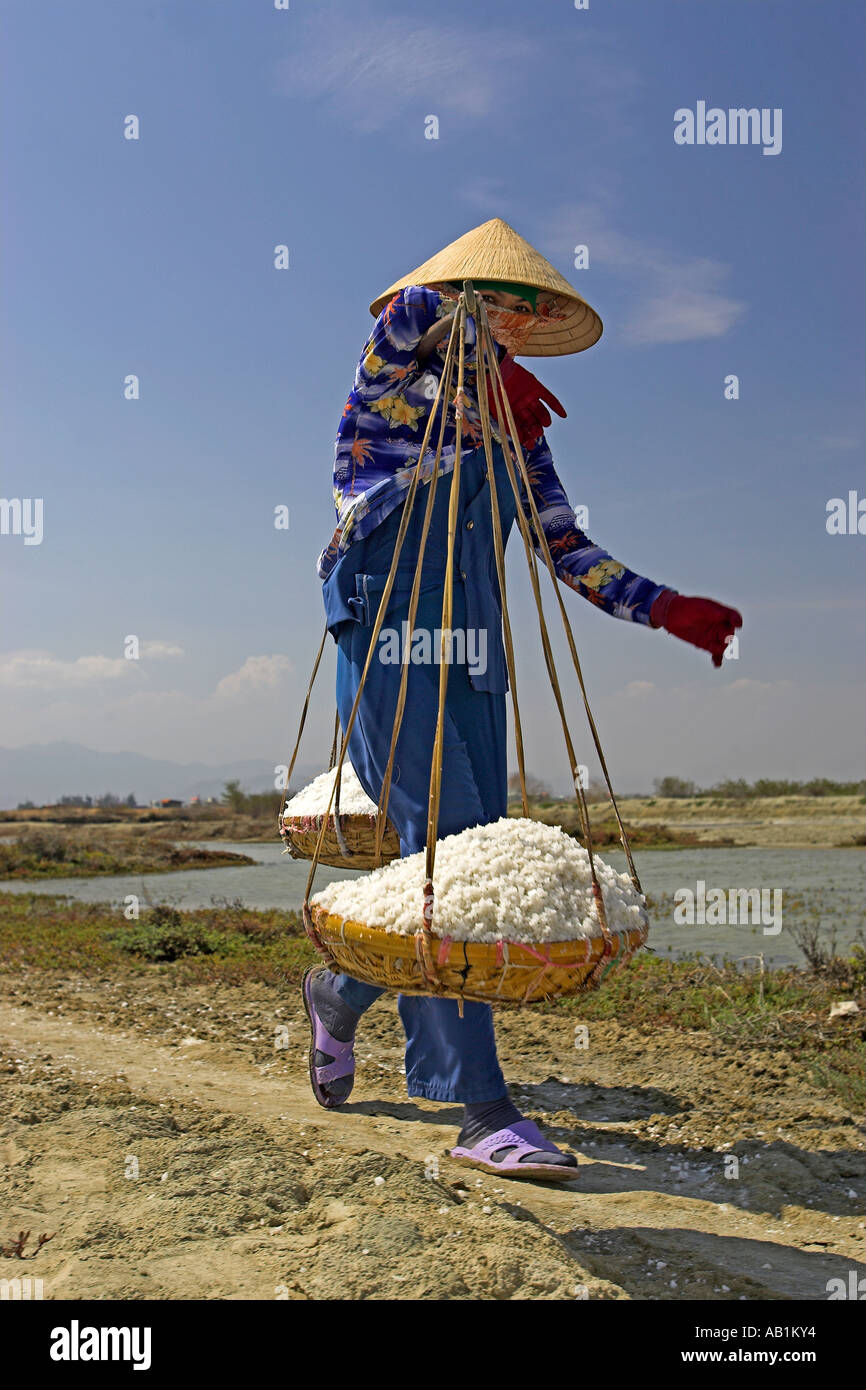 Woman in conical hat carries salt in wicker pannier baskets Phan Thiet ...